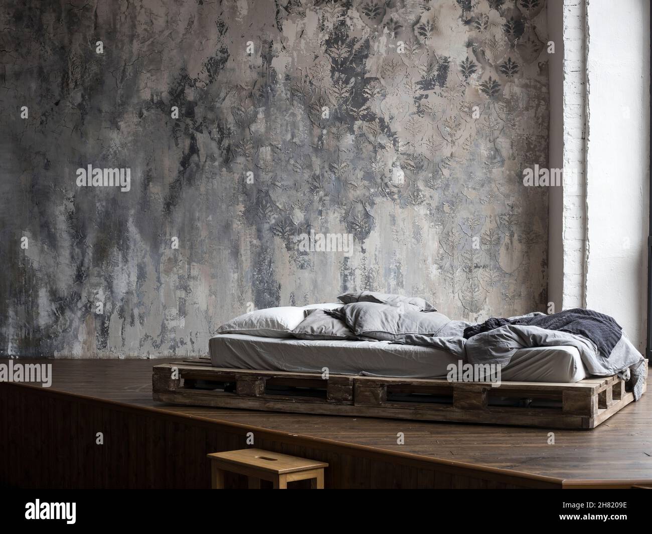 Unfilled bed made of wooden blocks with beige bedding in the bedroom ...