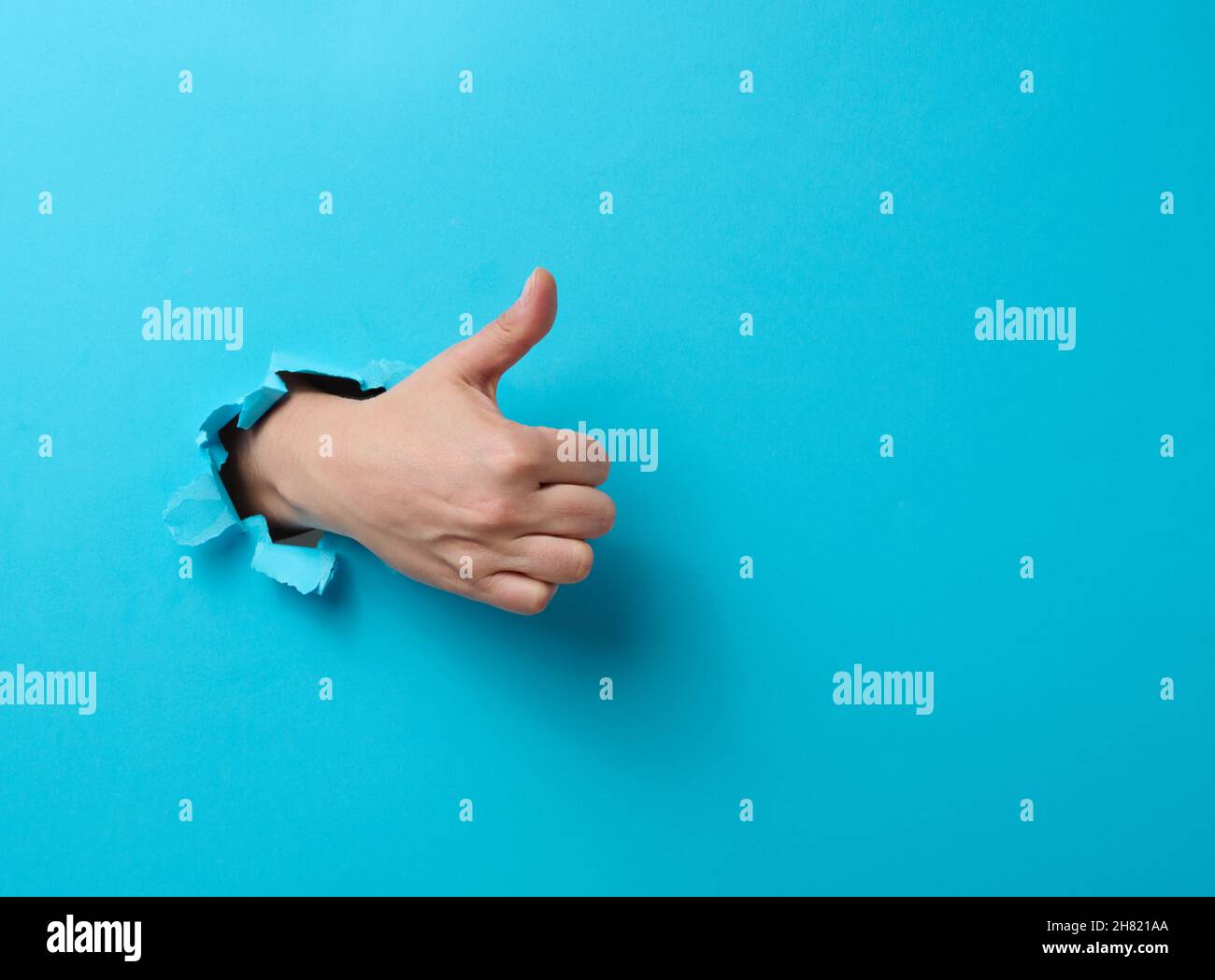 woman's hand sticks out of the torn hole and shows a gesture okay ...