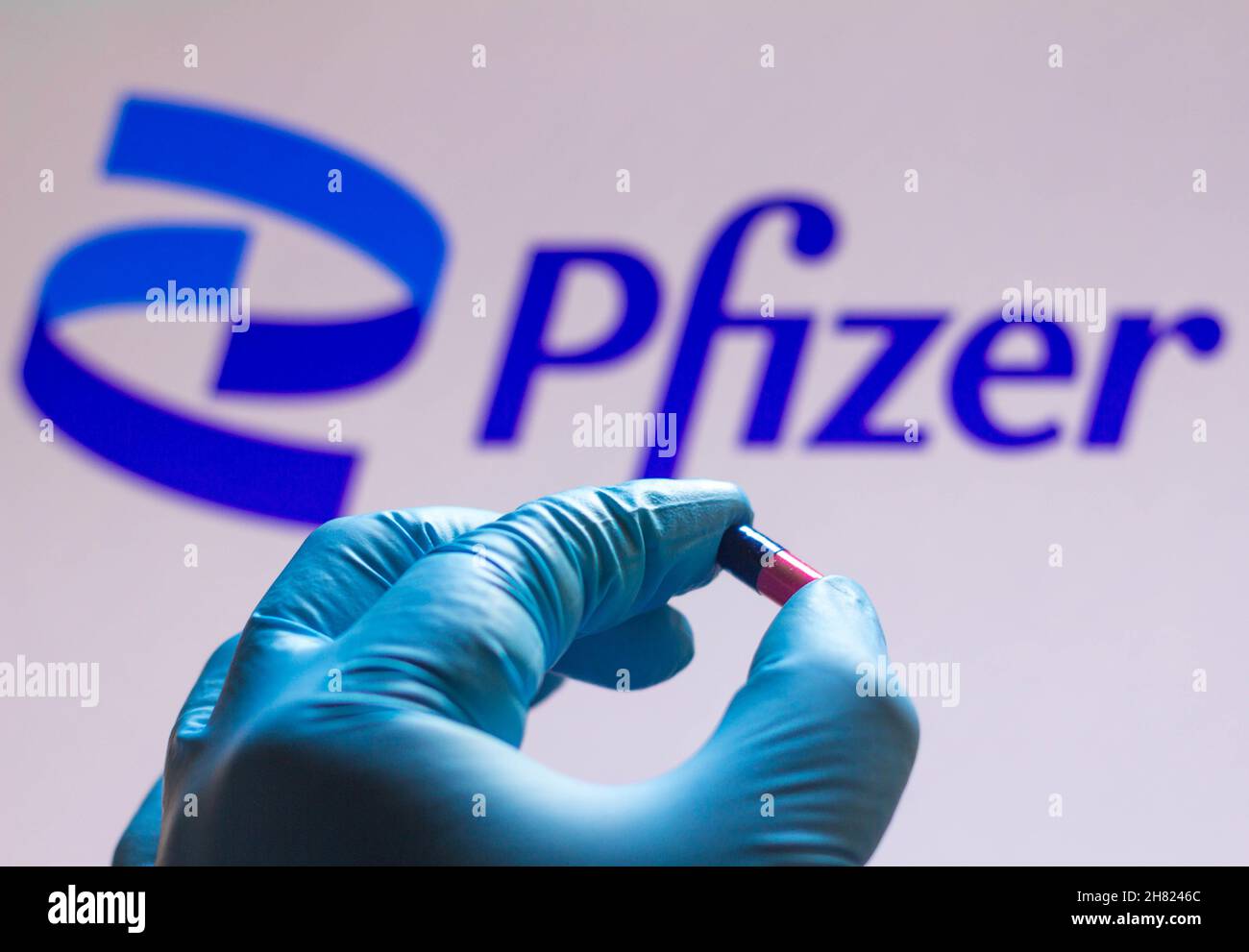 In this photo illustration a Pfizer logo is seen on a screen and a hand ...