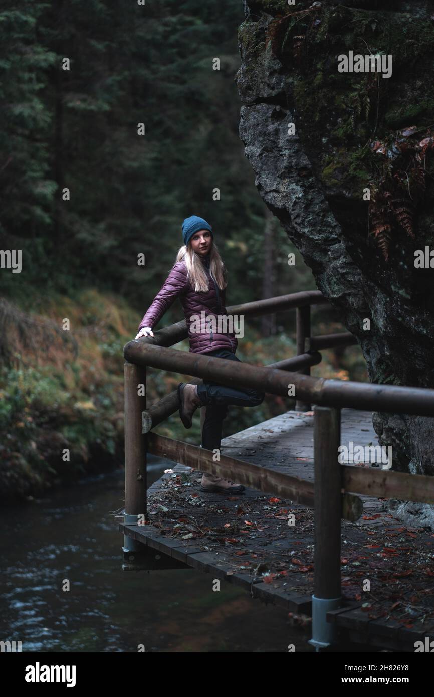 Adult blonde woman leaning on fences of a walkway in a forest in the ...