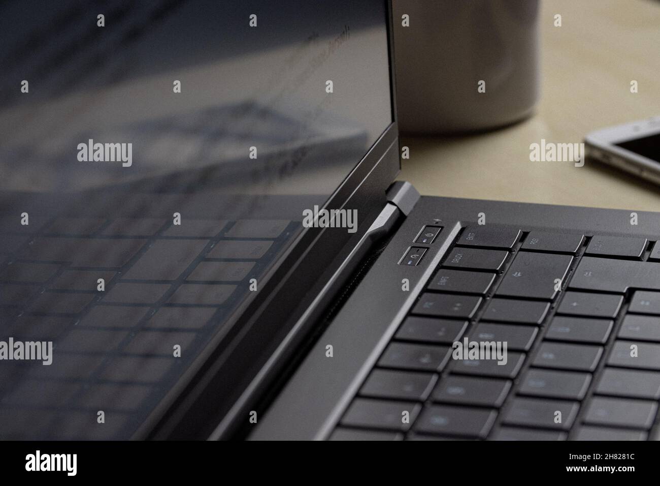Close up of a keyboard of a black laptop with a reflecting screen on a ...