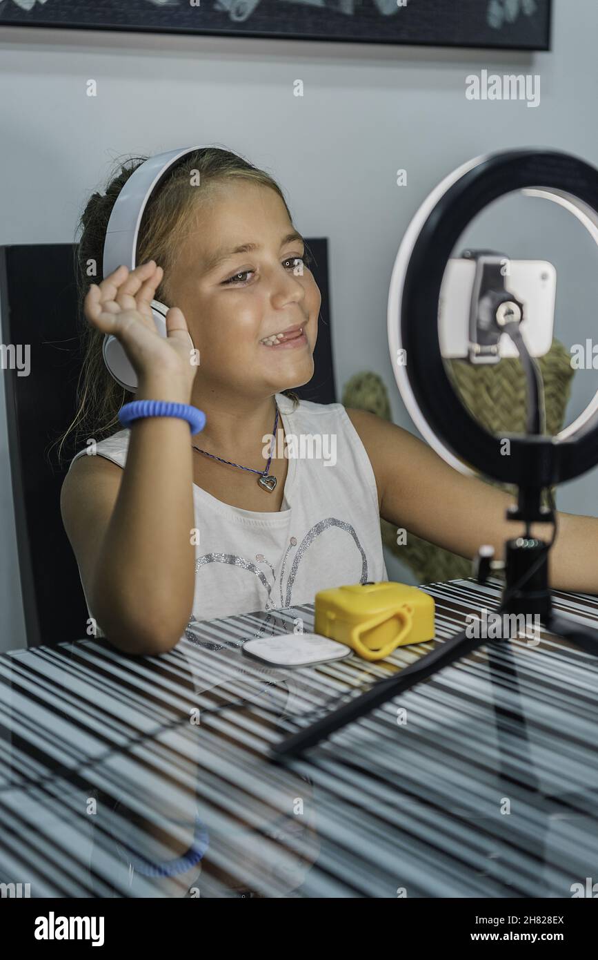 Little caucasian girl smiling while recording herself with mobile phone ...