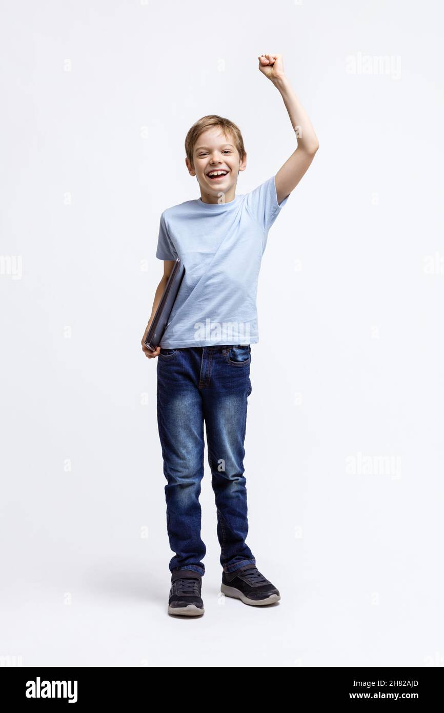 Happy young boy carrying laptop under one arm and lifting another one ...