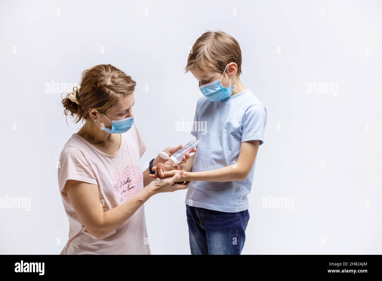 Young woman applying hand-sanitizer anti-bacterial gel on son's hands ...