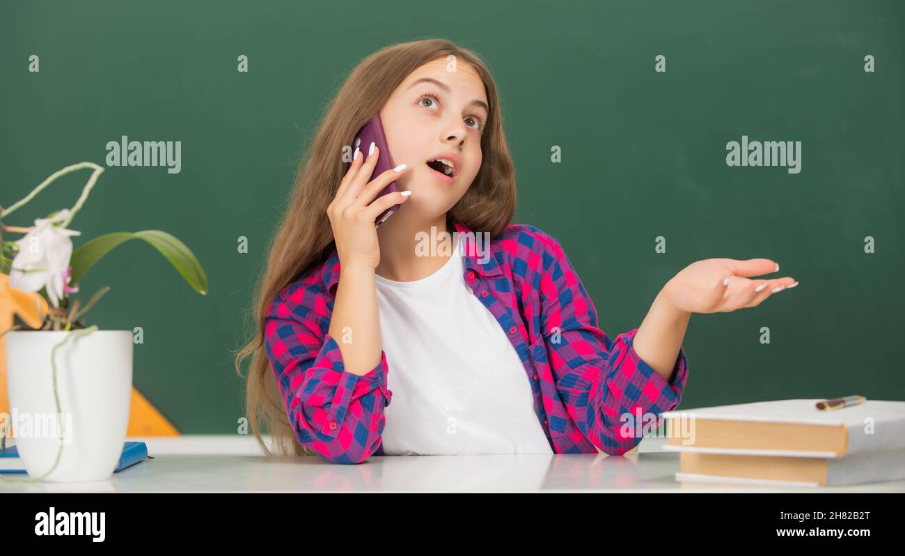 dreamy child at school talking on phone on blackboard background ...