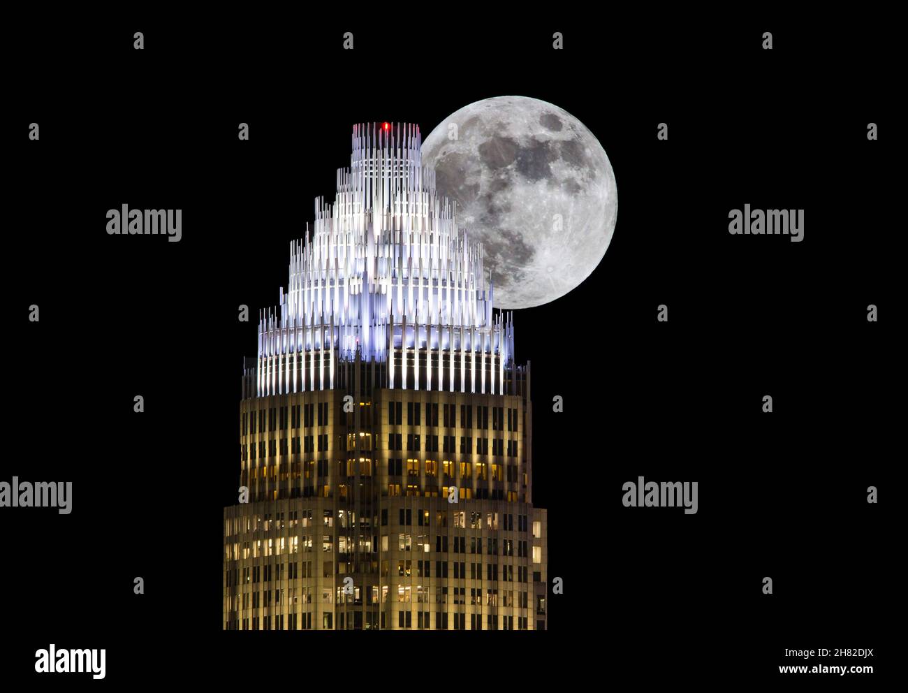 A full moon rises behind the Bank of America Corporate Center in ...