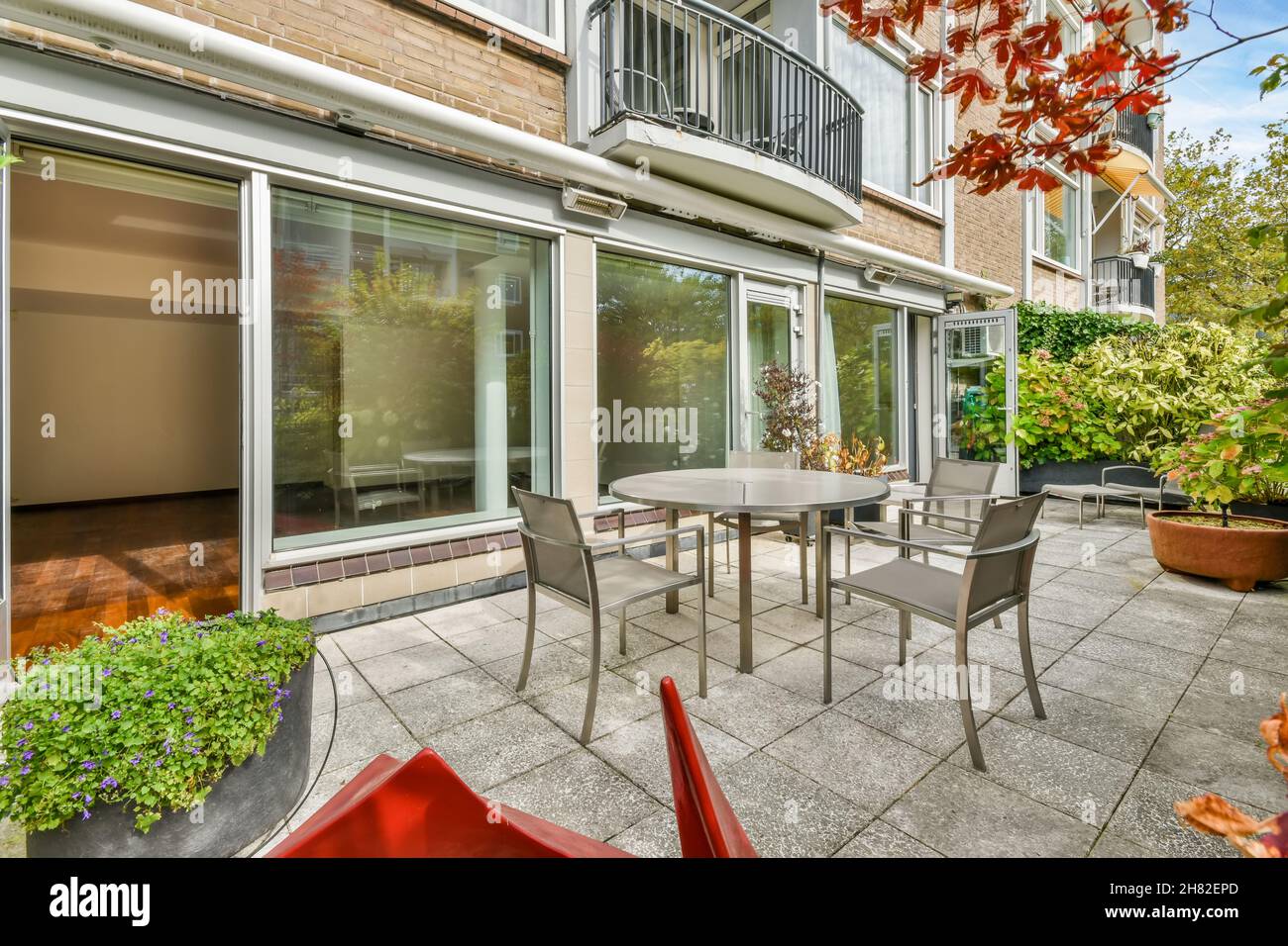 Cozy house courtyard with lots of greenery and modern table and chairs ...