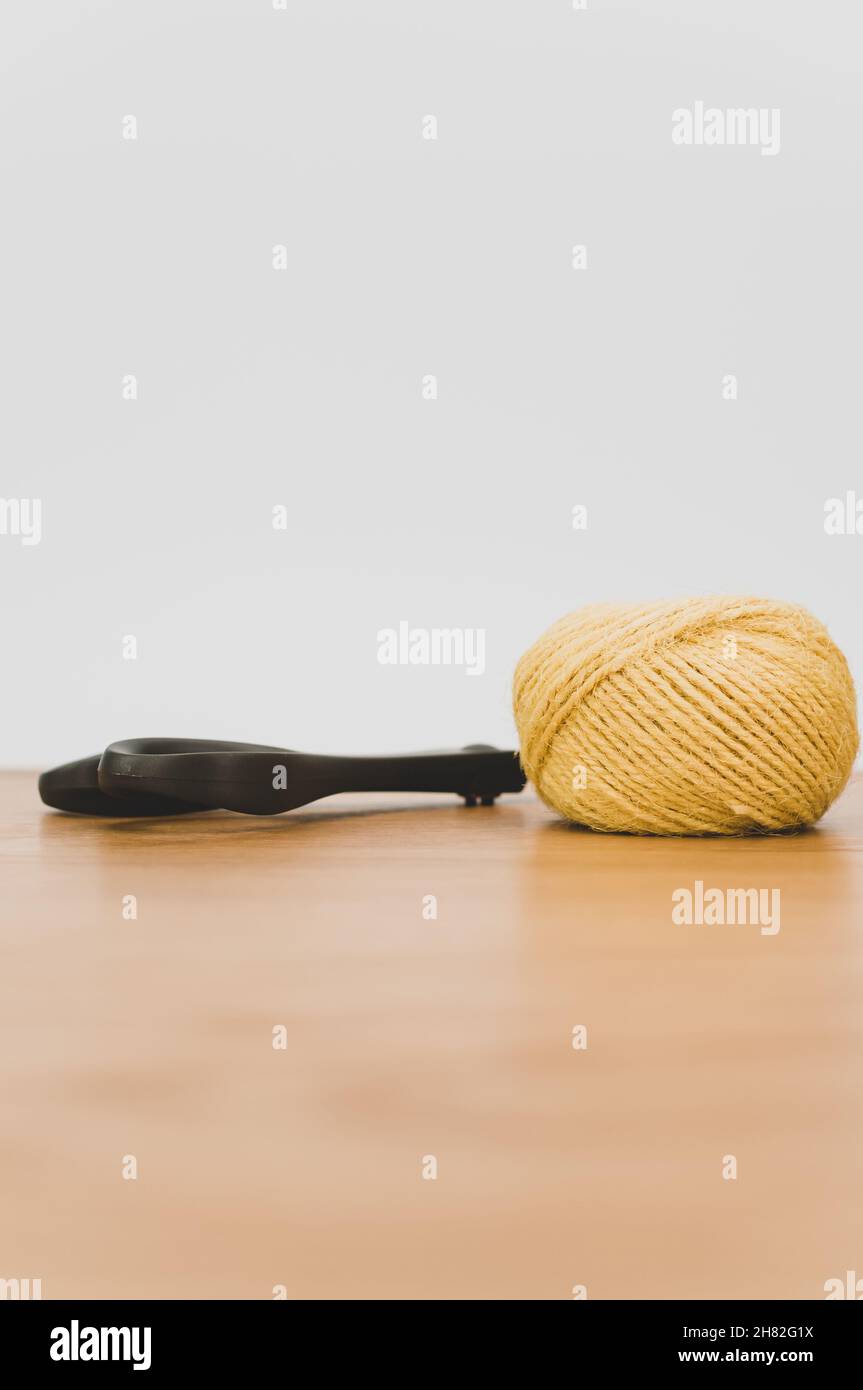 decorative rustic yellow yarn ball and scissors on a wooden tabletop ...