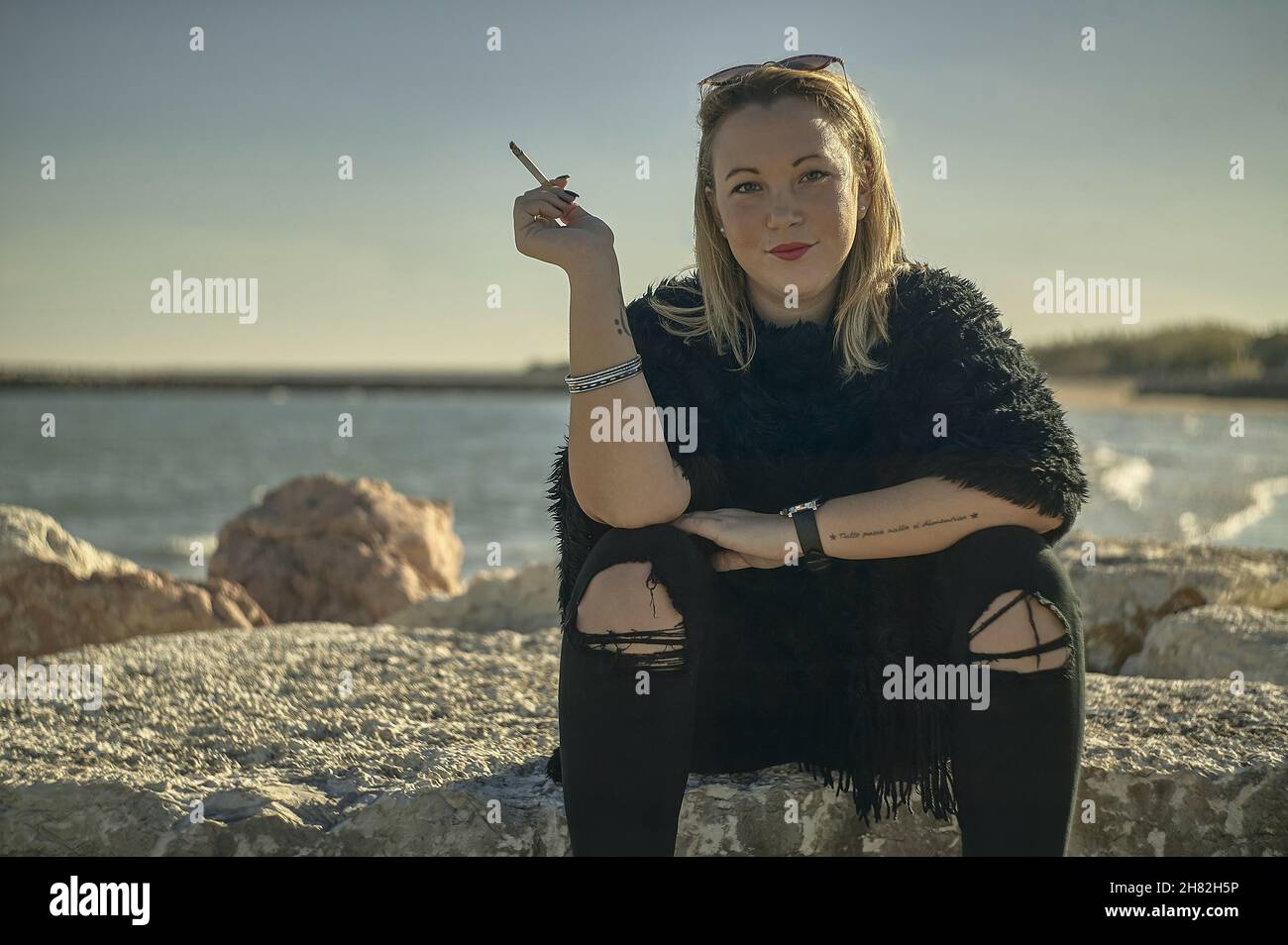 Smoking a cigarette sitting on the rocks Stock Photo - Alamy