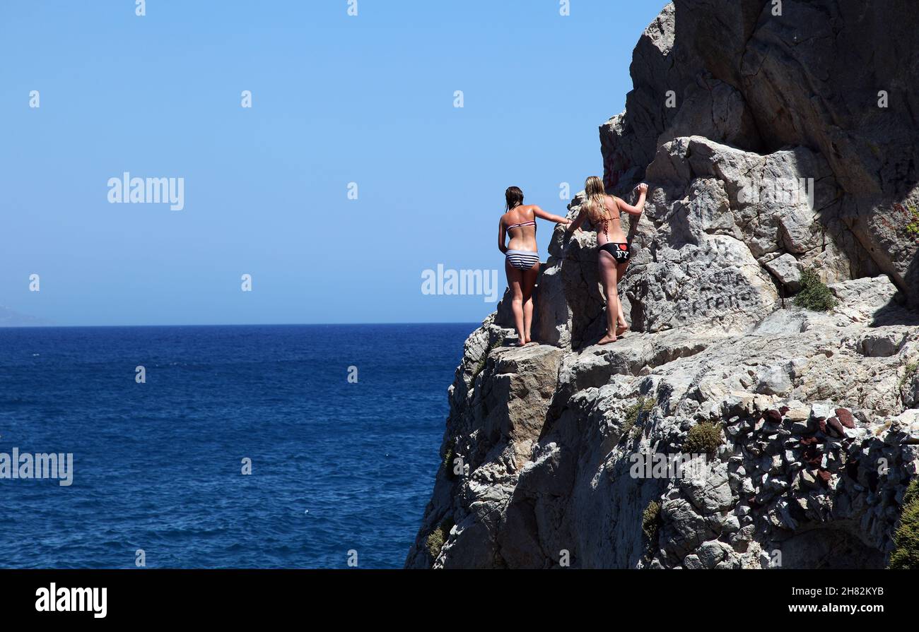 People ready to jumping in water from a rock at Kamari Beach in ...