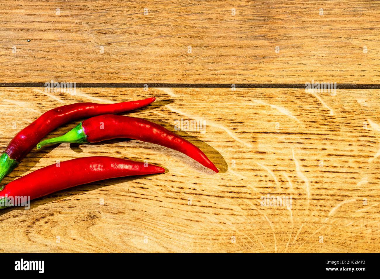 Top view of red chilli peppers on a wooden table under the lights Stock ...