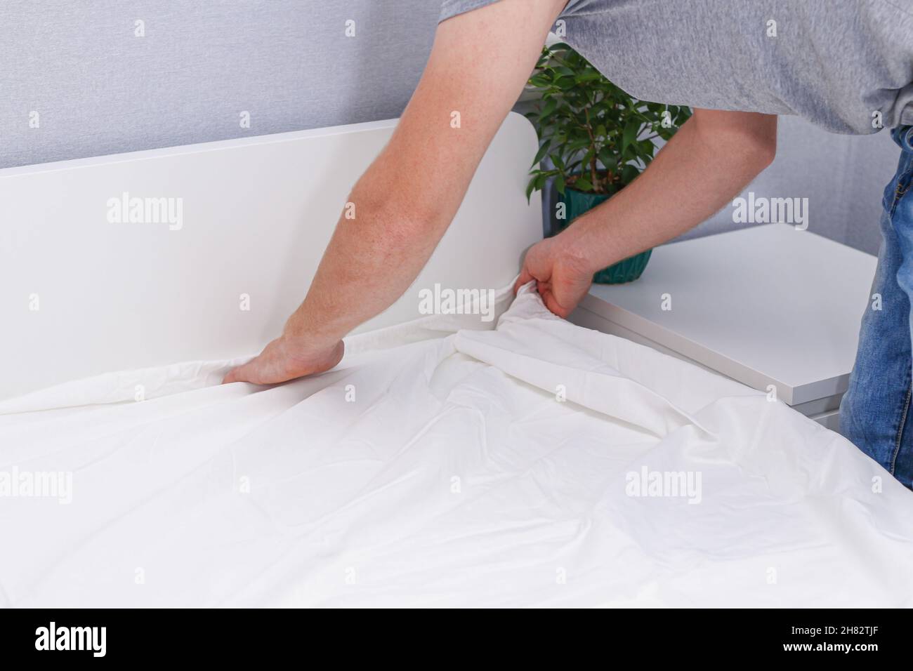 A man puts an elasticated sheet on the mattress. Change of bed linen ...