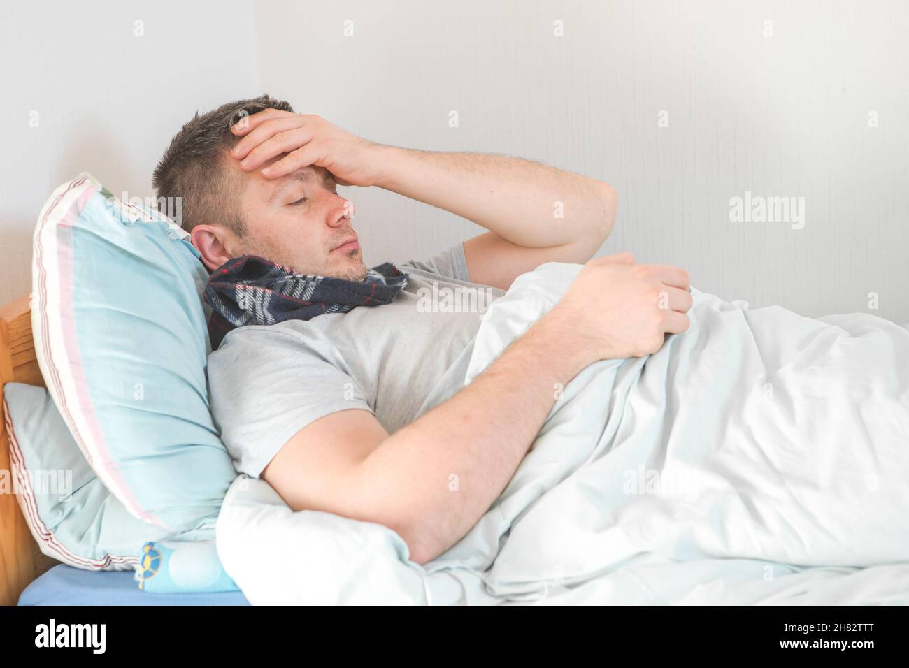 Illness man sitting on bed and holding his head. Boy suffering from ...