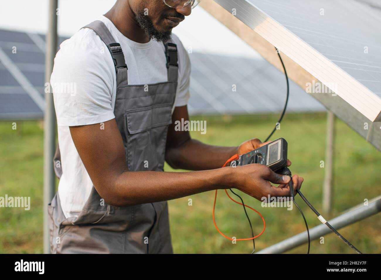 Close up of african american man in grey overalls measuring resistance ...