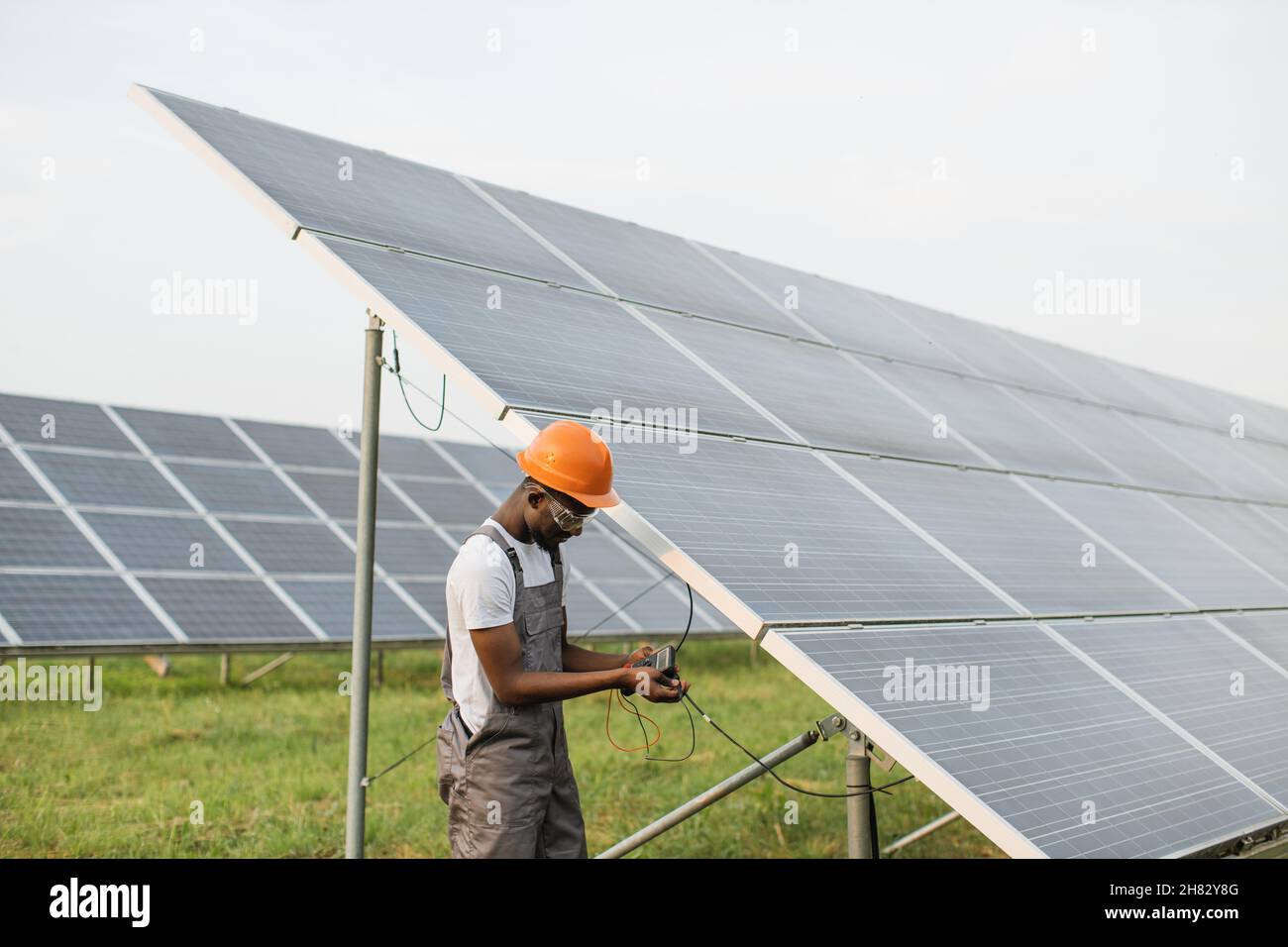 Professional african engineer in helmet and uniform using multimeter ...
