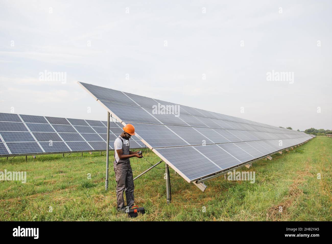 Professional african engineer in helmet and uniform using multimeter ...