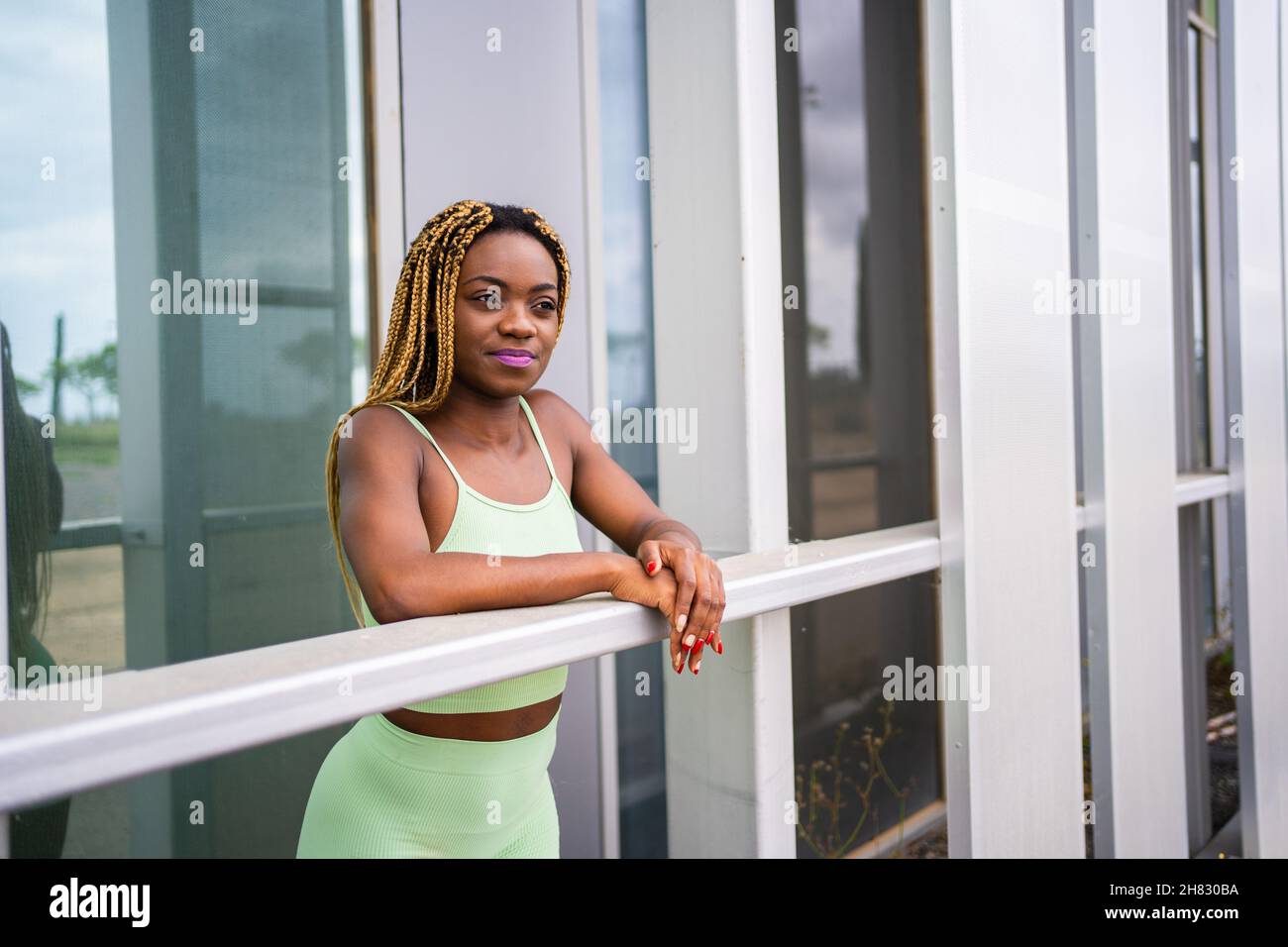 African woman leaning on the railing of a modern building in sports ...