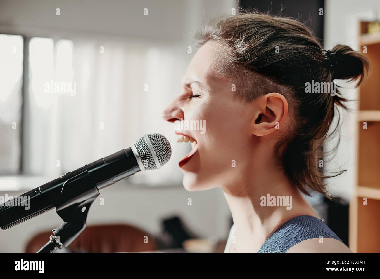 young emotional woman singing into a microphone. female rock singer on ...