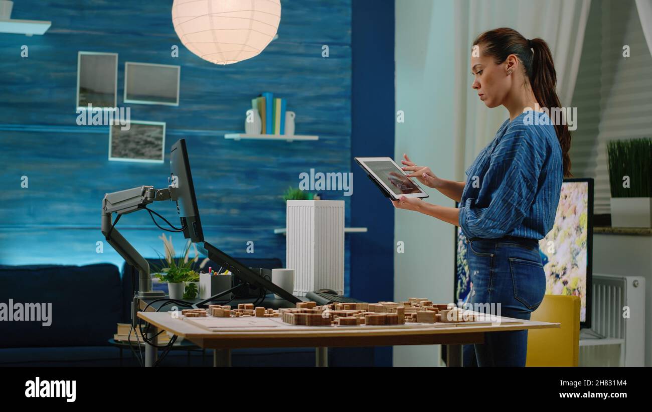 Architect looking at digital tablet with building model to design ...