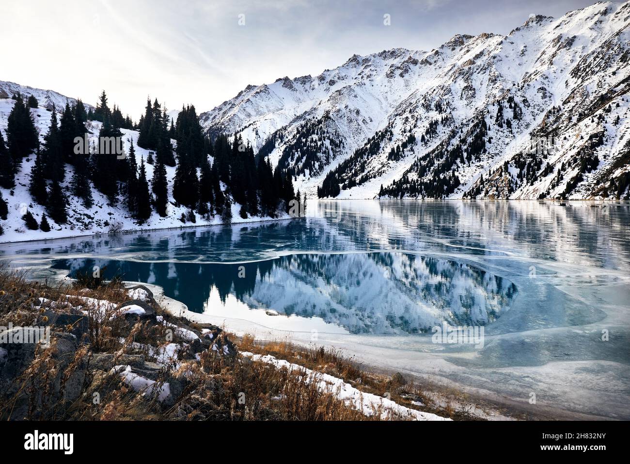 Big Almaty lake in the mountains with blue ice and spruce forest at ...