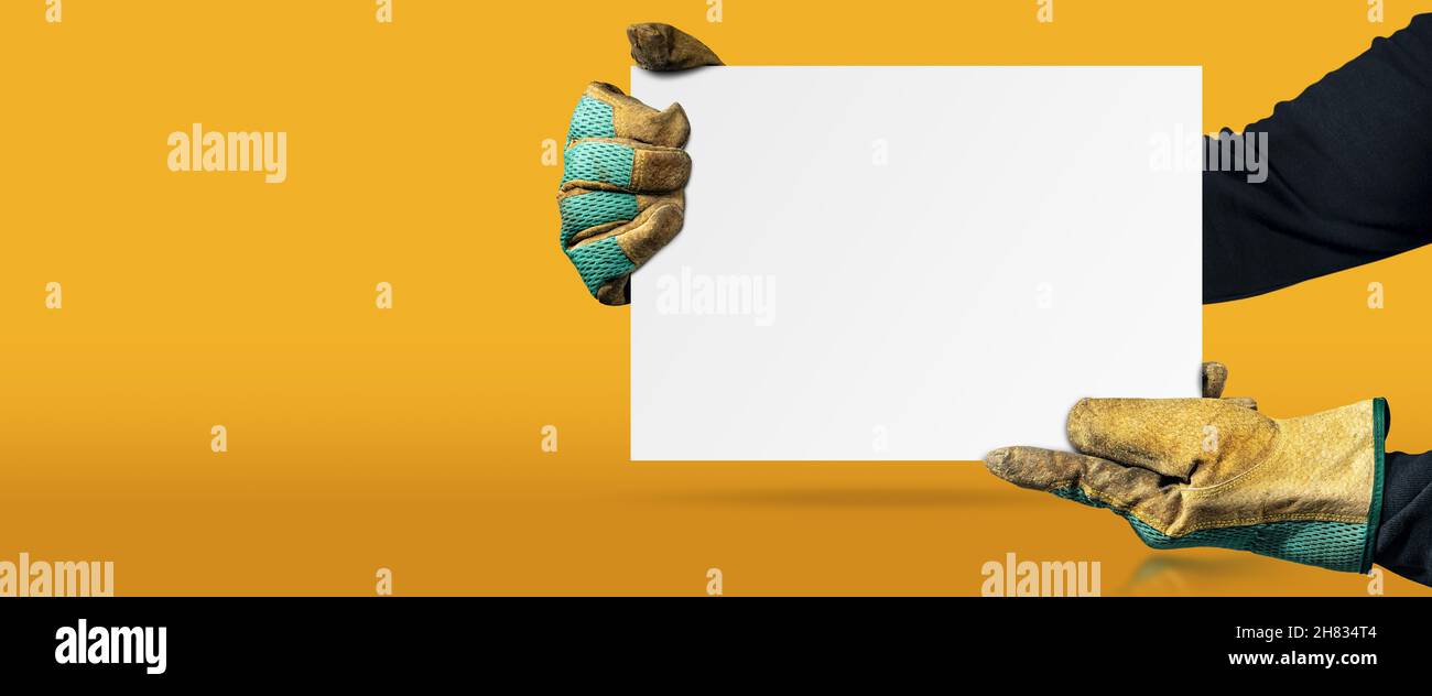 Manual worker with protective work gloves holding a blank banner on ...
