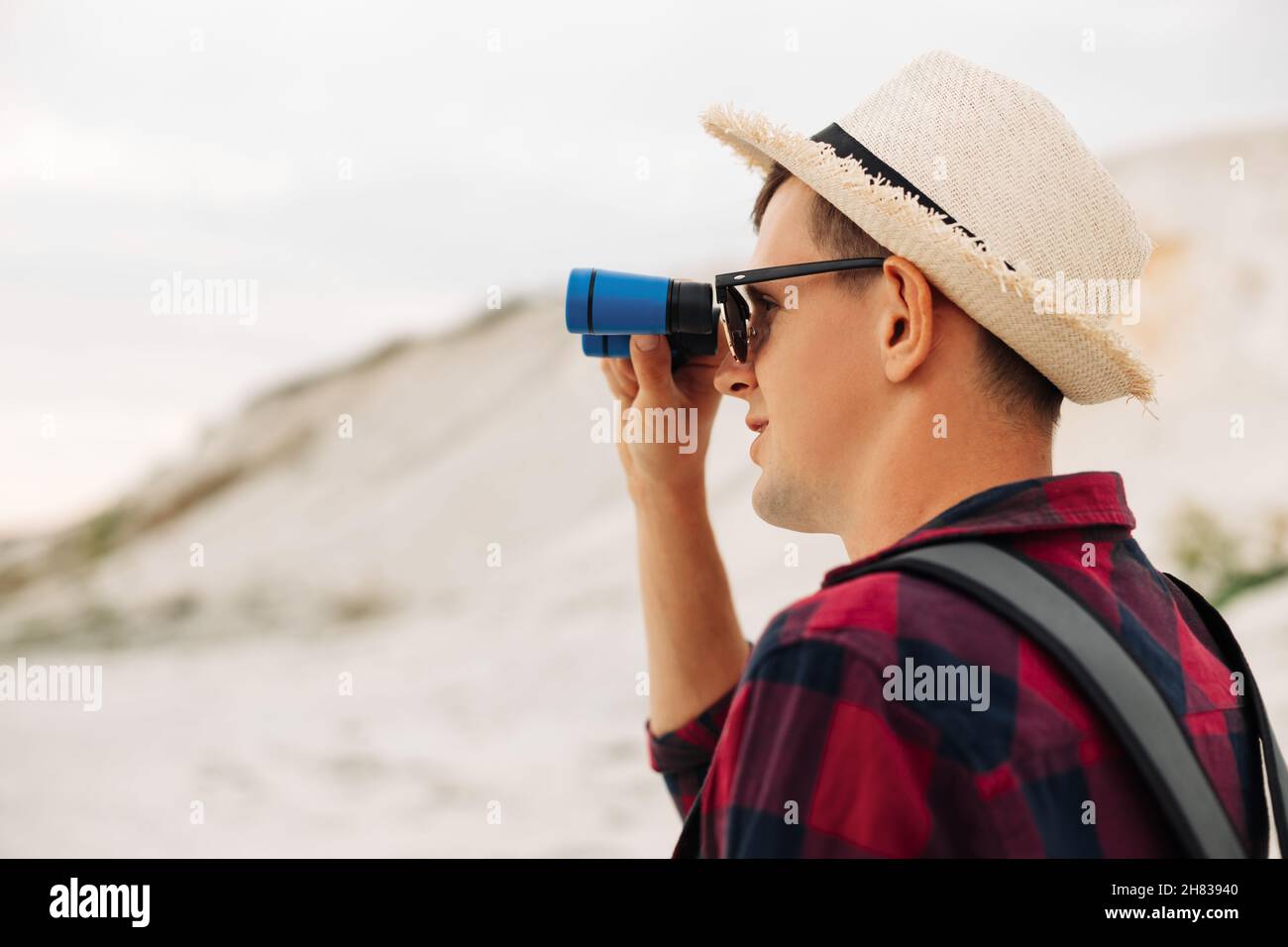 Male traveler with a backpack looking through binoculars outdoors in ...