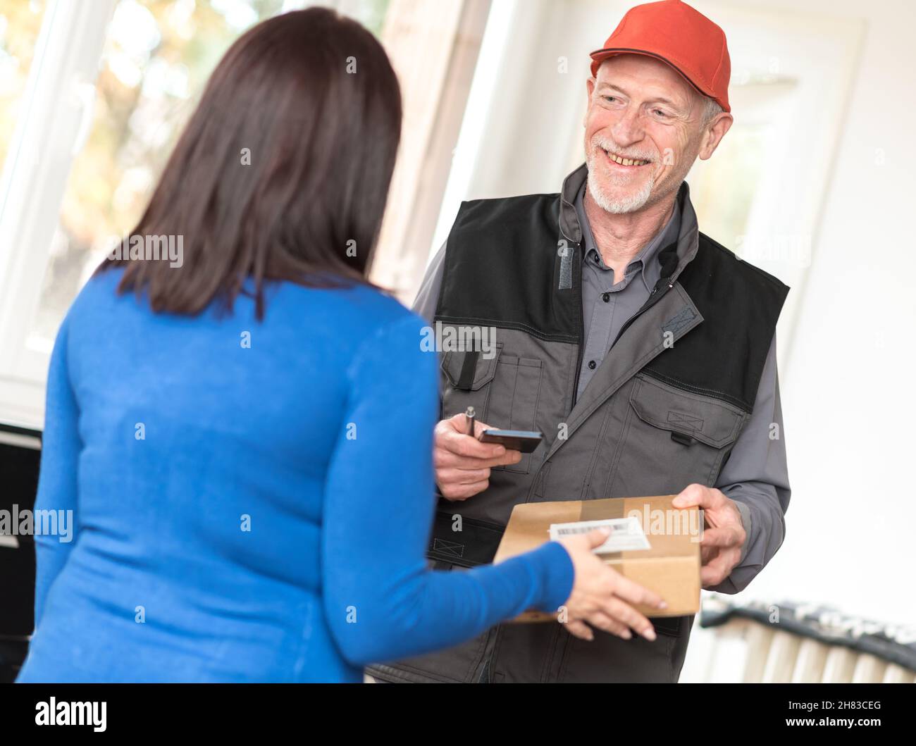 Woman receiving package from smiling delivery man Stock Photo - Alamy