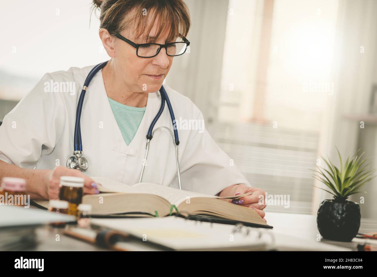 Female doctor reading a textbook in medical office Stock Photo - Alamy