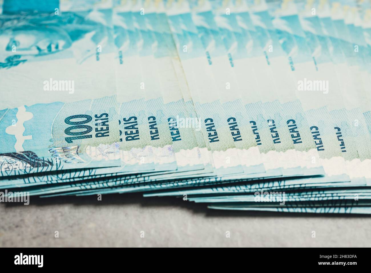 Large bundle of Brazilian money, 100 reais banknotes, gray background ...