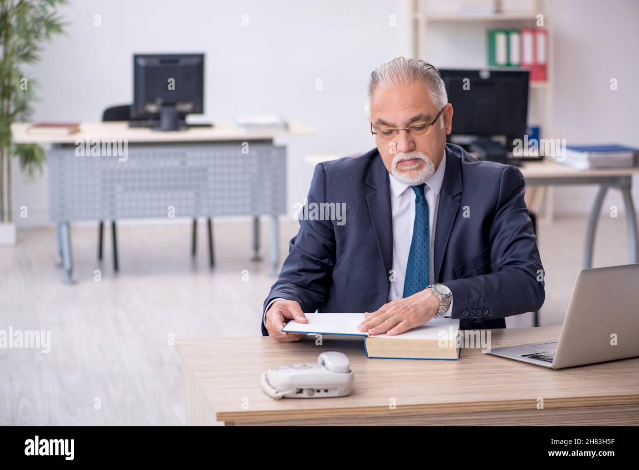 Old businessman employee reading book at workplace Stock Photo - Alamy
