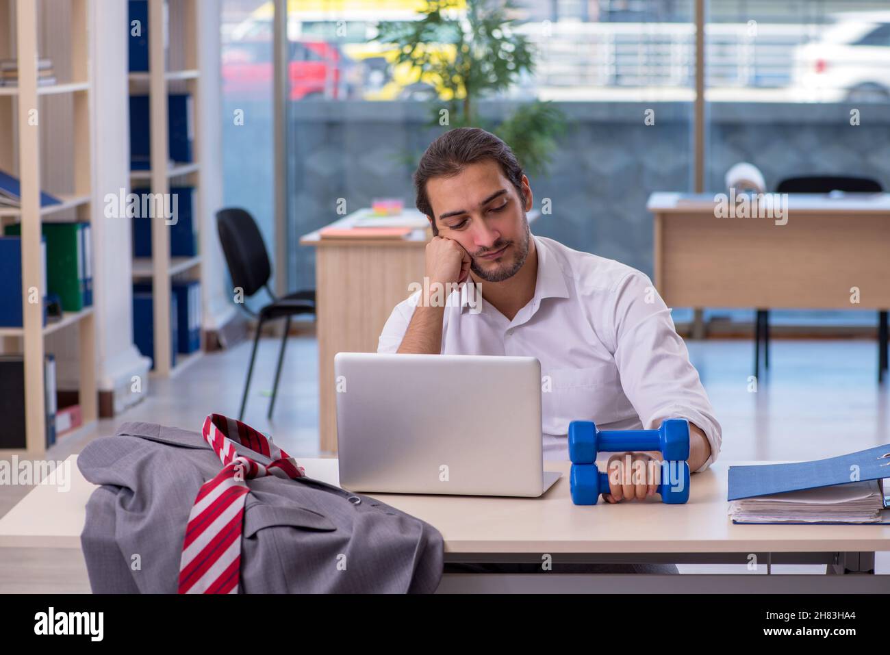 Young employee doing sport exercises at workplace Stock Photo - Alamy