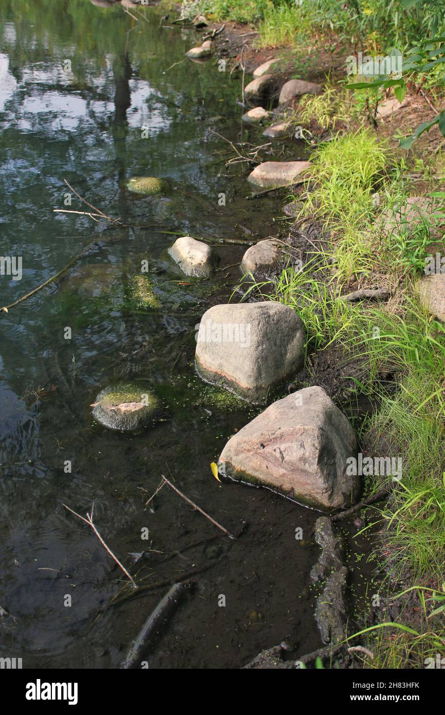 Classic natural shore lined with stones and rocks in the bright summer ...