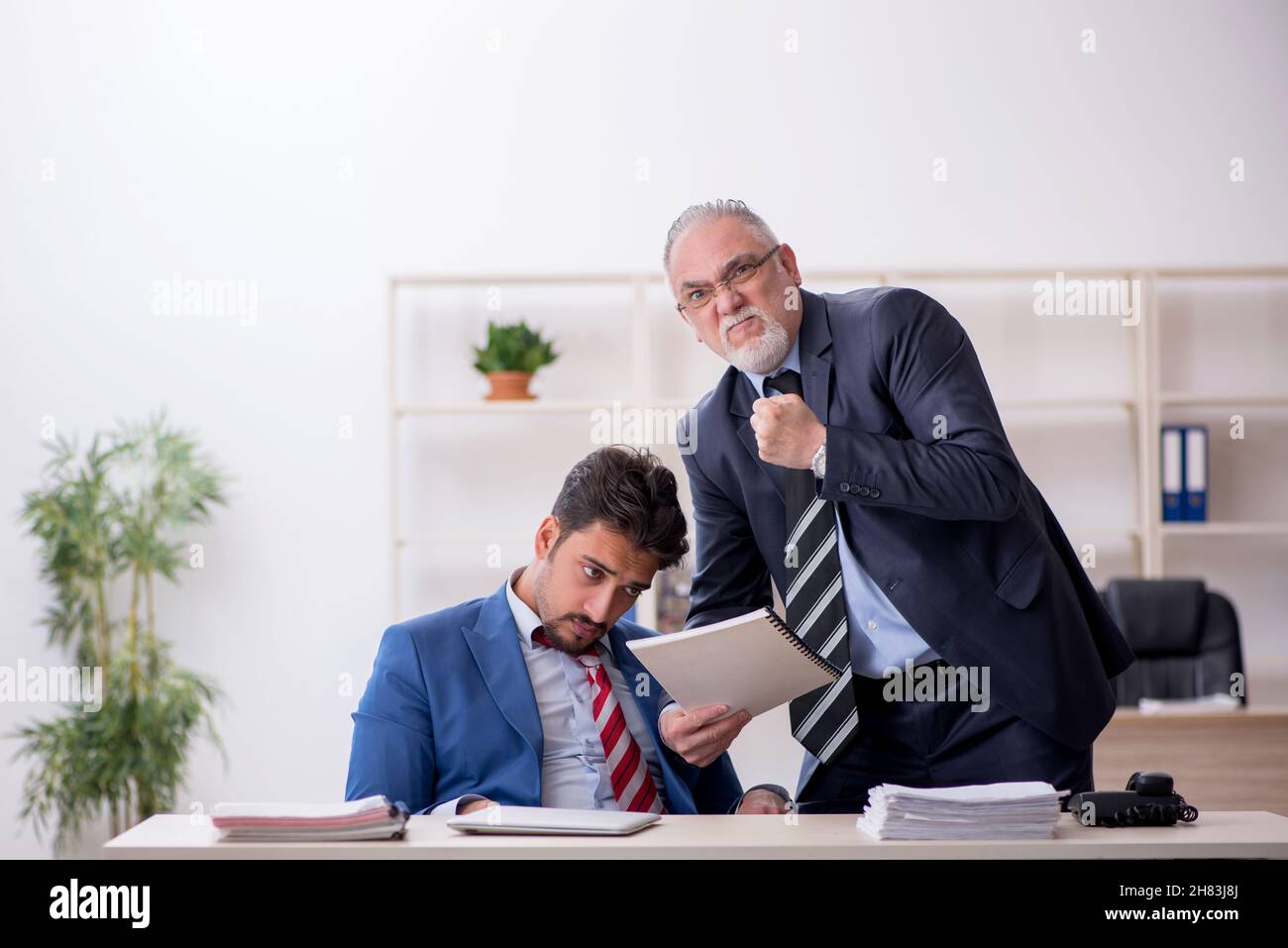 Old boss and young employee in bullying concept Stock Photo - Alamy