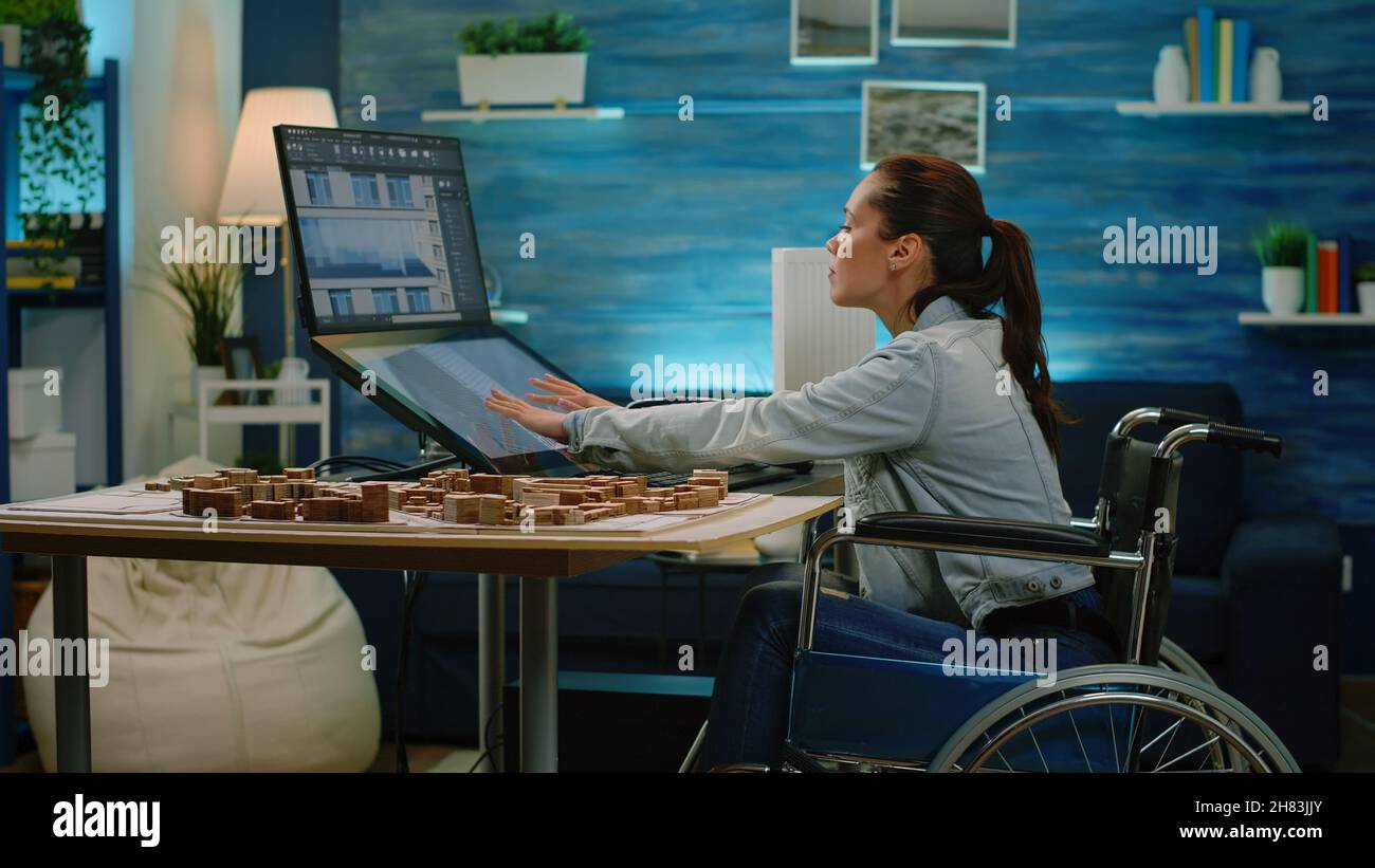 Disabled architect analyzing building model on touch screen monitor for ...