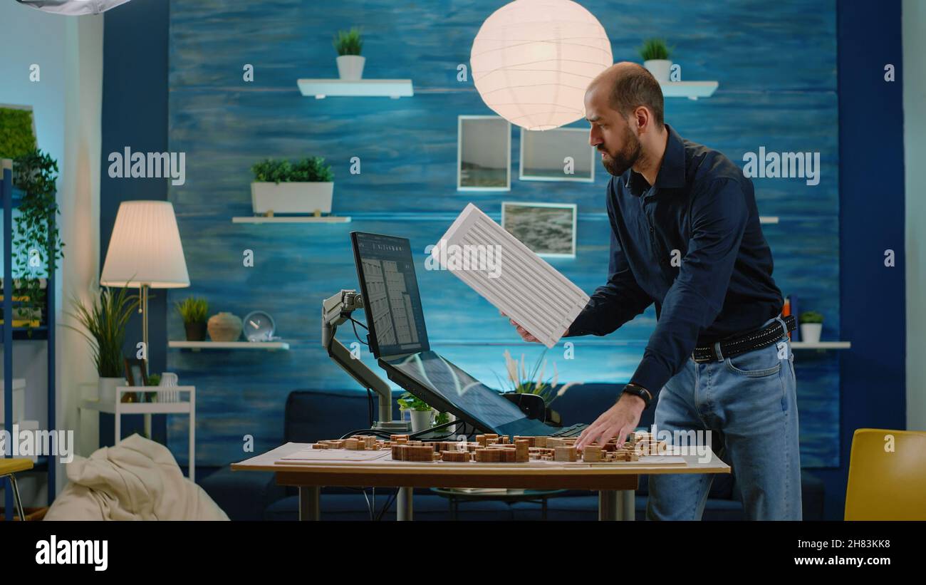 Architect Looking At Maquette And Construction Layout On Table For Architectural Development