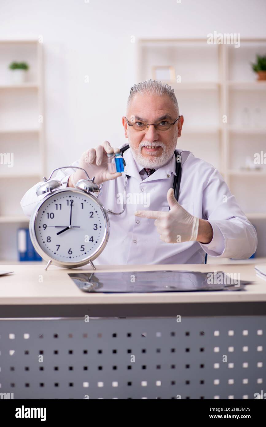 Old doctor in time management concept Stock Photo - Alamy