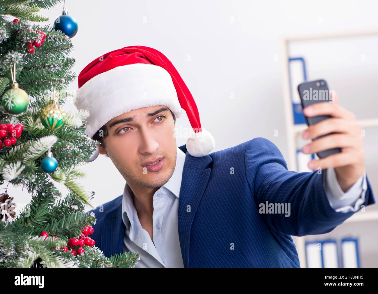 The young employee celebrating christmas at workplace Stock Photo - Alamy