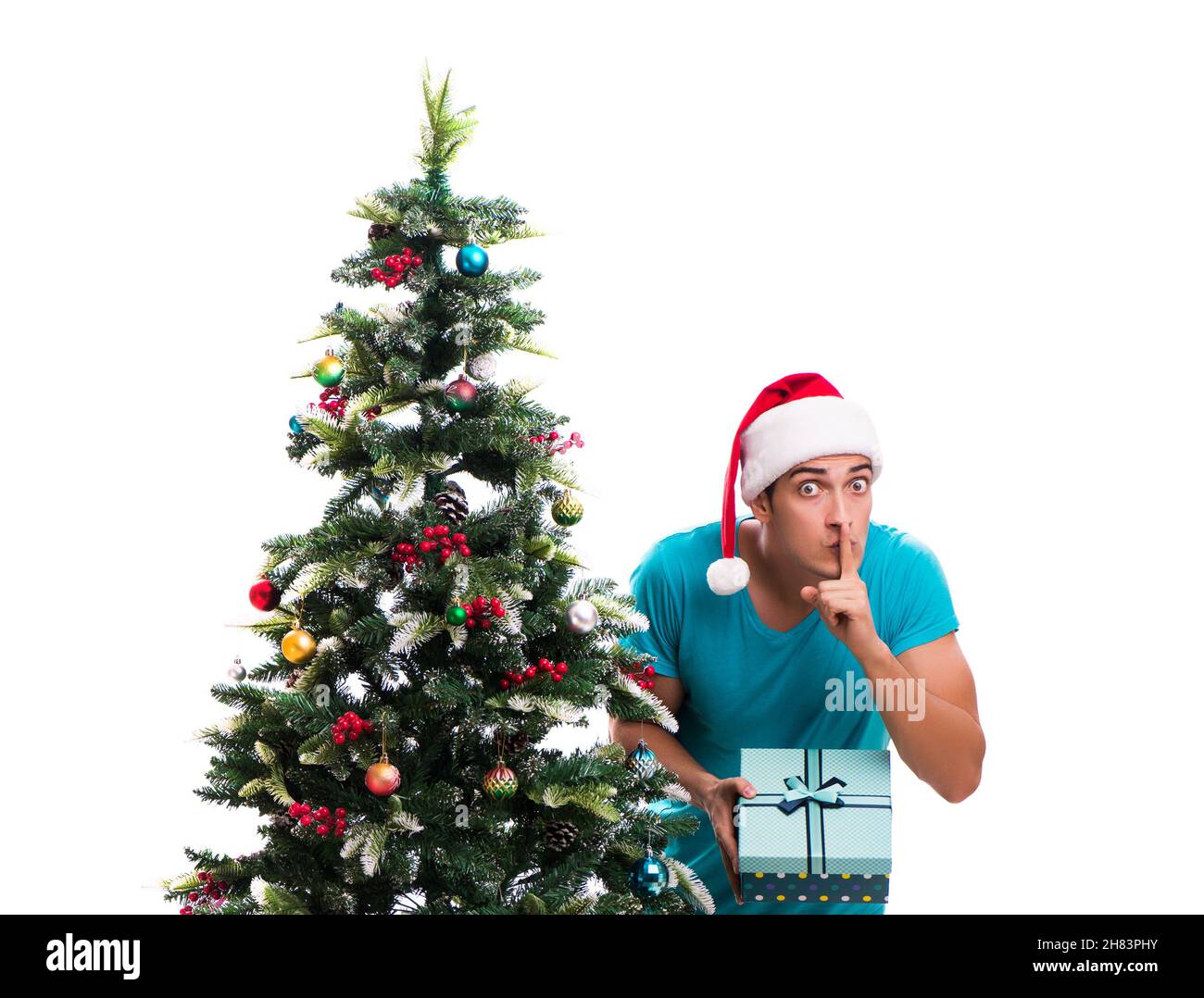 The young man decorating christmas tree isolated on white Stock Photo ...