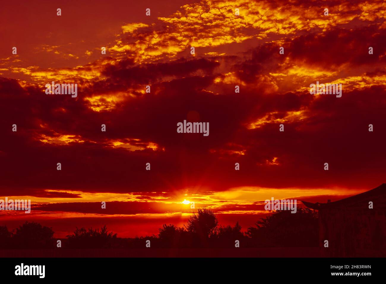 Setting sun make rays through the cloudy red sky Stock Photo - Alamy