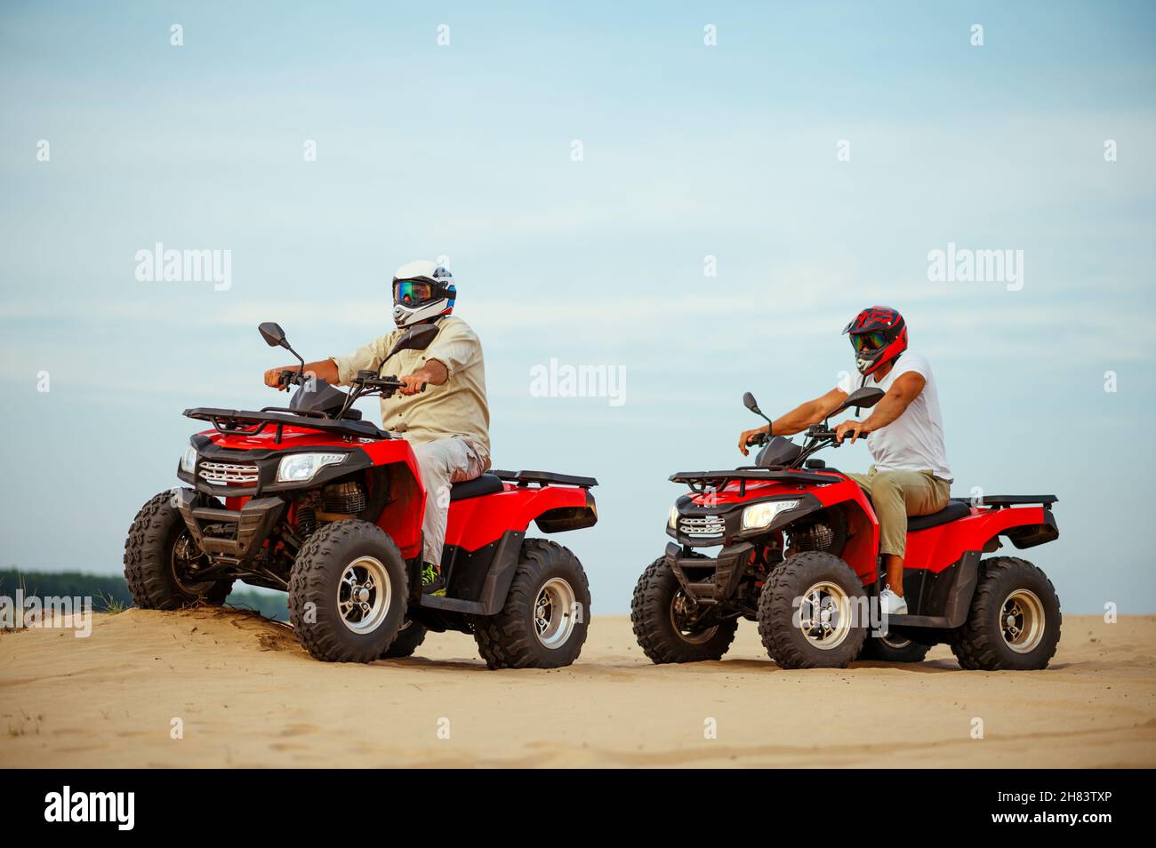 Two men in helmets, atv riding in desert sands Stock Photo - Alamy