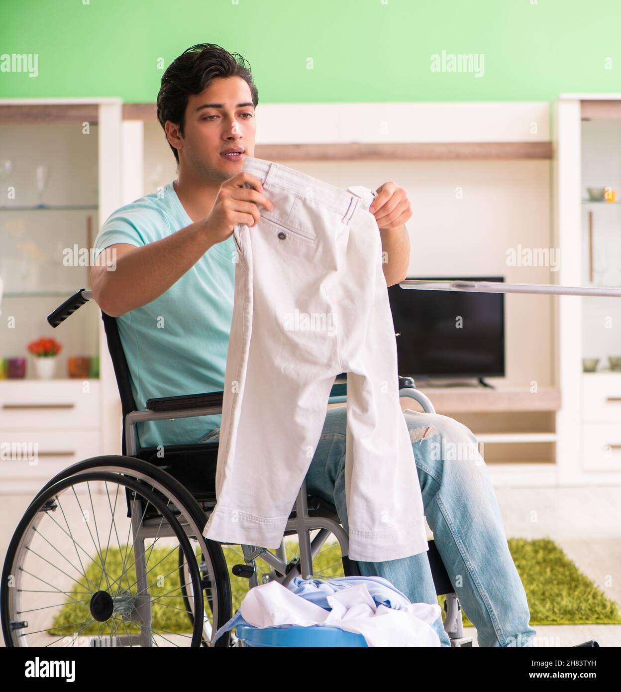 The disabled man on wheelchair doing laundry Stock Photo - Alamy