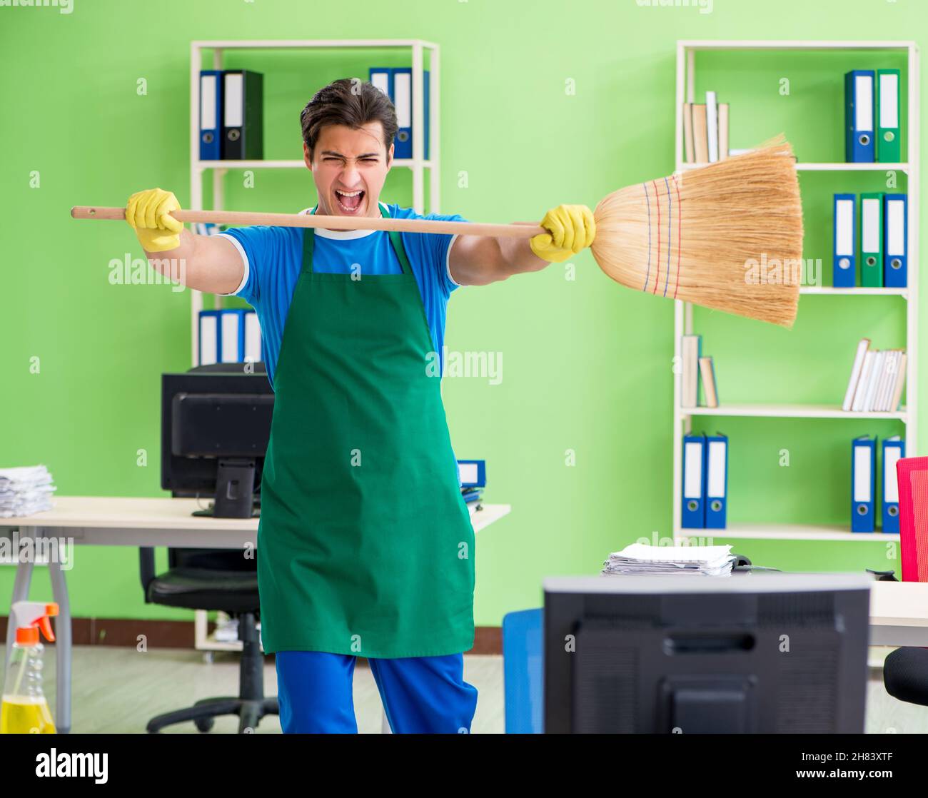 Young male handsome professional cleaner cleaning floor with broom ...
