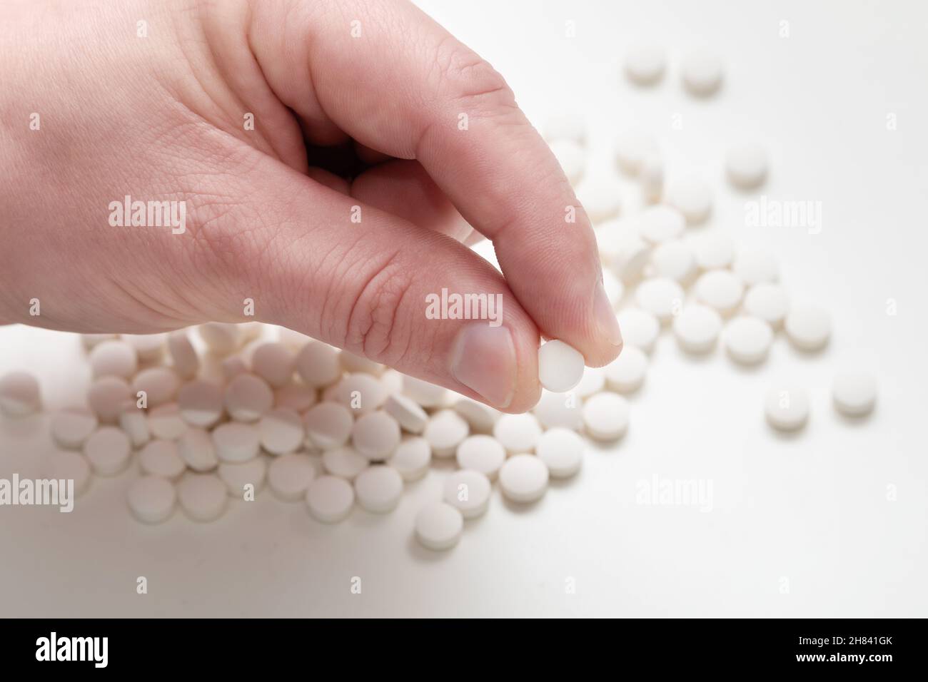 One white round pill in a hand. Vitamin pills Stock Photo - Alamy