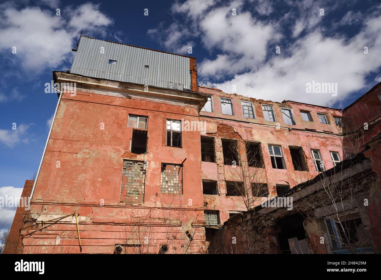 Abandoned red brick Soviet factory with broken windows against clowdy ...