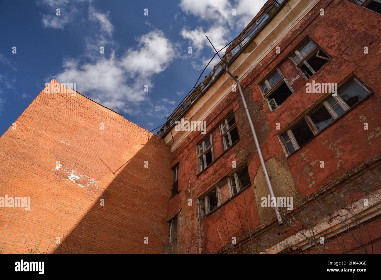 Abandoned red brick Soviet factory with broken windows and downpipe ...