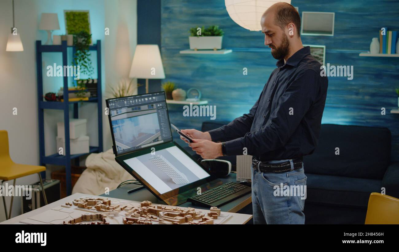 Man architect looking at tablet with building design plan for ...