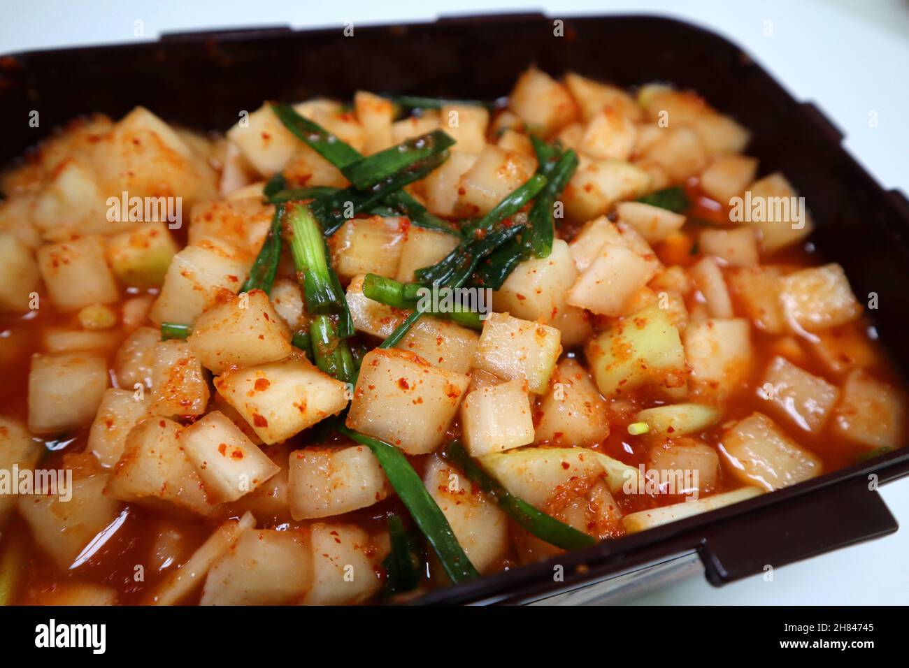 Tray of diced radish kimchi with greens isolated on a white background ...