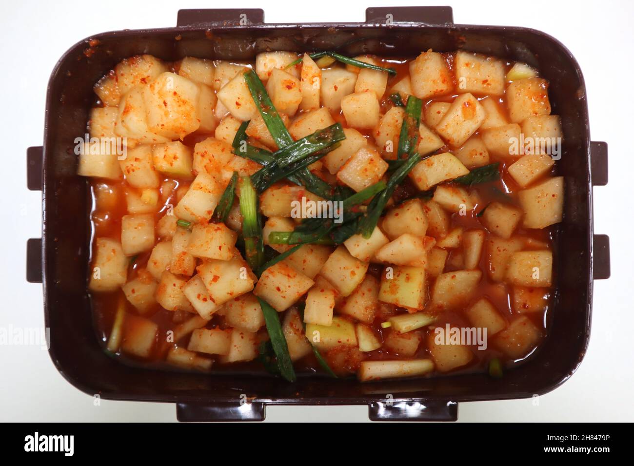 Tray of diced radish kimchi with greens isolated on a white background ...