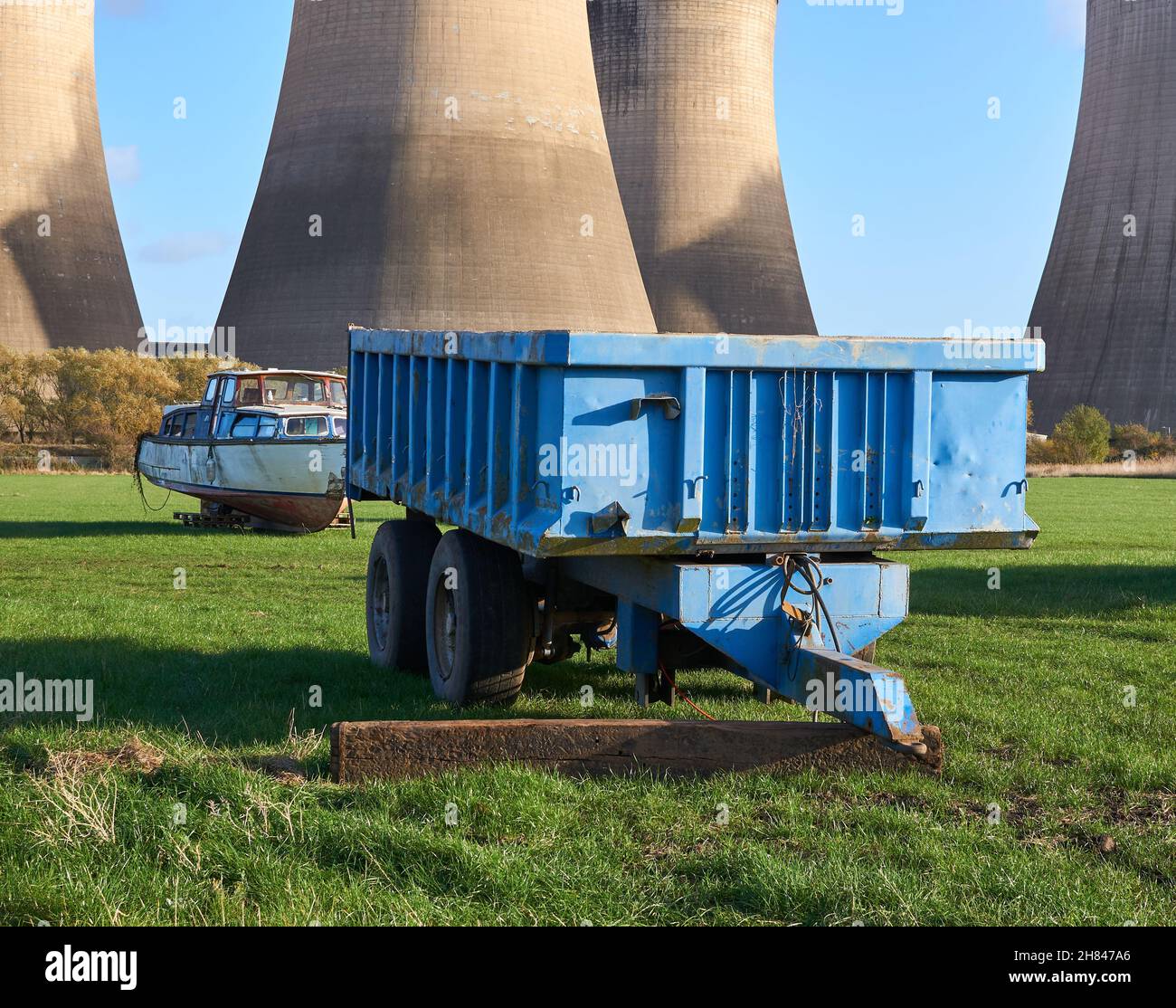 Farm trailer and boat in a field near a power station Stock Photo - Alamy