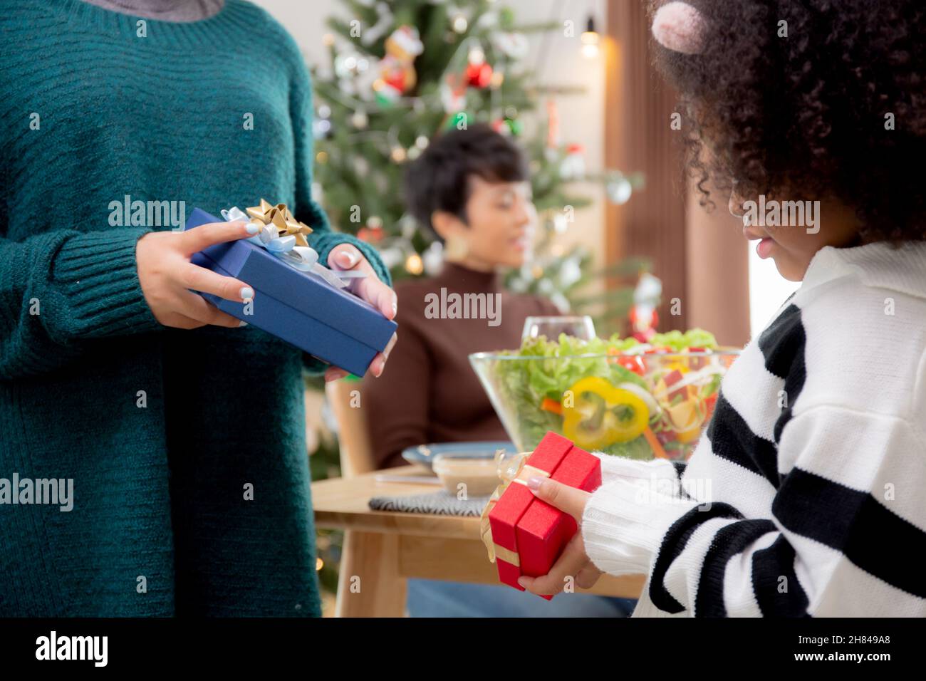 Happy family with sibling giving gift box surprising during dinner ...